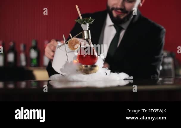 Skillful caucasian barkeeper in black stylish suit decorating alcoholic ...