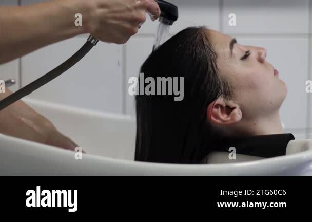 Beautiful young caucasian girl hairdresser washing long brown hair ...