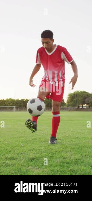 Vertical video of biracial football player on field kicking ball. Male ...