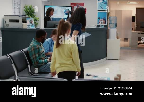 Mother with child and patients in waiting area hospital reception to ...