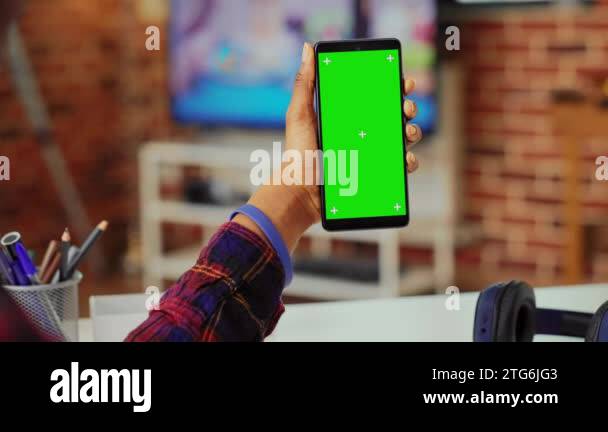 Young student looking at greenscreen display on mobile phone, analyzing ...