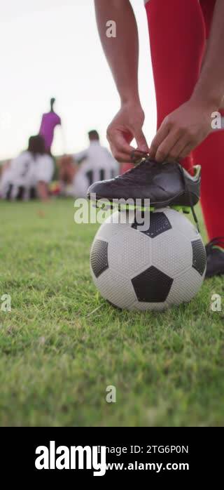 Vertical video of biracial football player on field kicking ball. Male ...