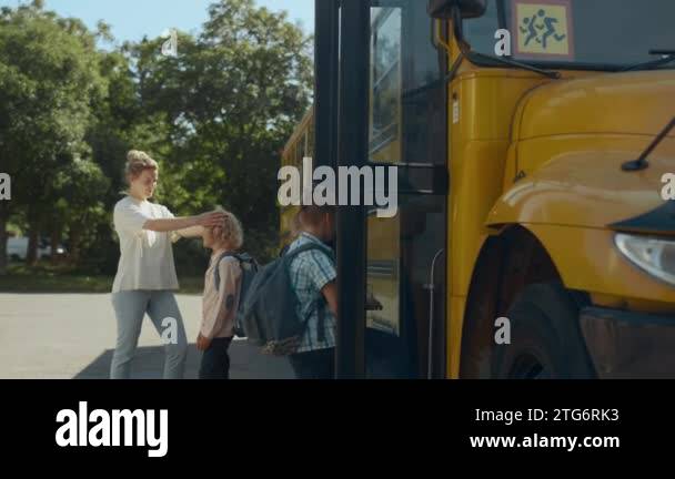 Mother saying goodbye little cute son standing at yellow bus. Diverse ...