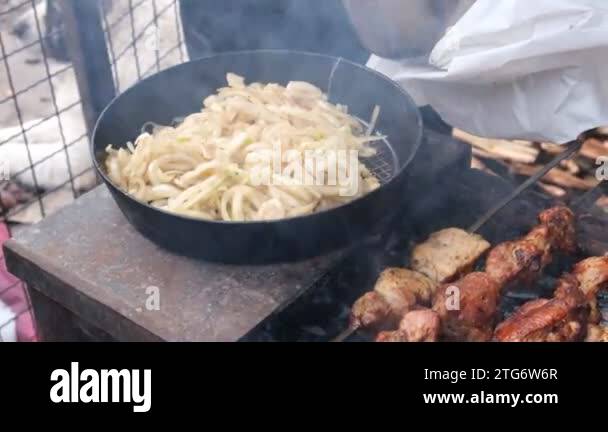 a man roasts meat on a fire. Onion and barbecue. Grilling pork neck ...