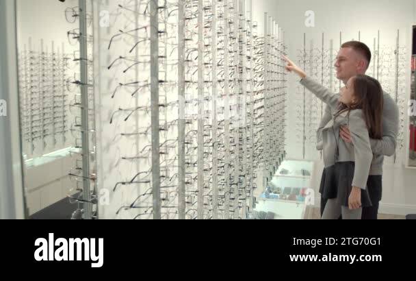 Teenage girl with father near shop window in modern opticians shop ...