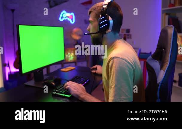 Pro gamer streaming video games with green screen mock-up display in ...