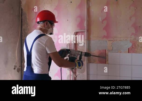 Contractor removes of ceramic tiles facing of a wall. Workman doing ...