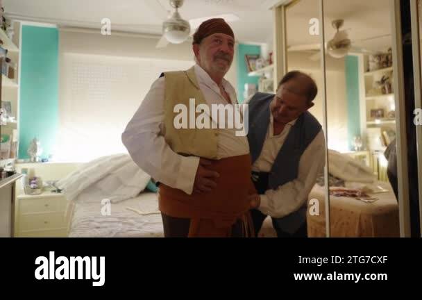 Older Caucasian man putting on the sash of the traditional costume of ...