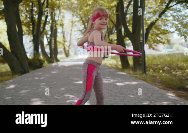 Athletic fitness toddler girl training playing twisting Hula hoop ...