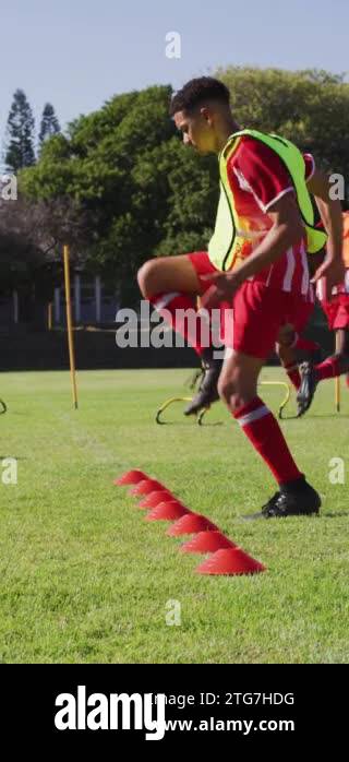 Vertical video of biracial football player on field kicking ball. Male ...