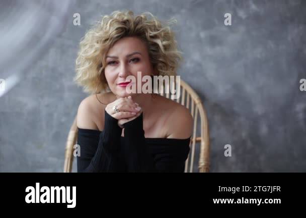 Attractive woman in black longsleeve sitting on chair in front of ...