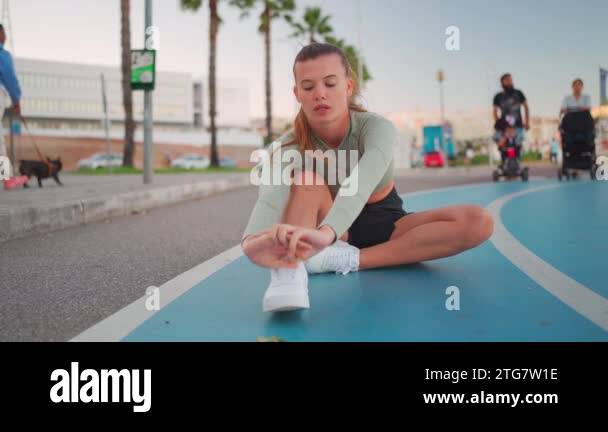Woman runner stretching leg muscles by touching his shoes sitting on ...