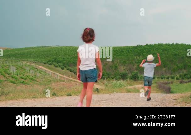 Two kids (boy and girl) on the country road filmed from the back. Boy ...