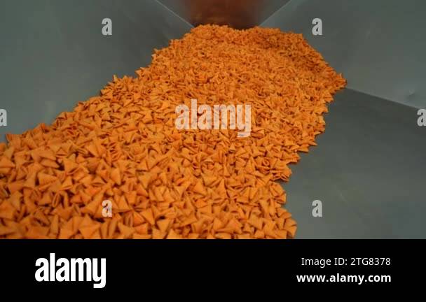 Pouring cone-shaped chips onto the production line in a food factory ...