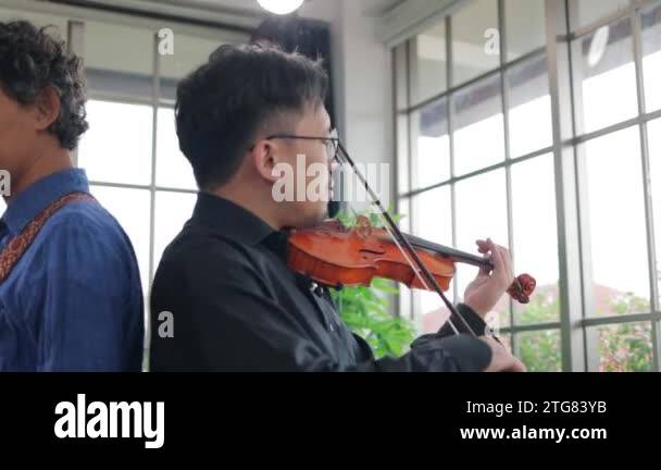 Two Asian musicians play classical instruments violin and electric ...