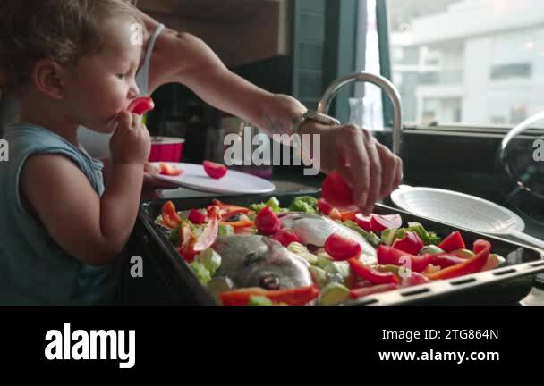 Mother teaches her little son how to cook healthy food in the kitchen ...