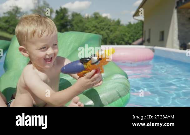 CLOSE UP: Little boy enjoying at water fight game while floating in ...