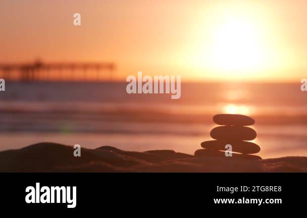 Stack of pebble stones, sandy ocean beach, sunset sky. Rock balancing ...