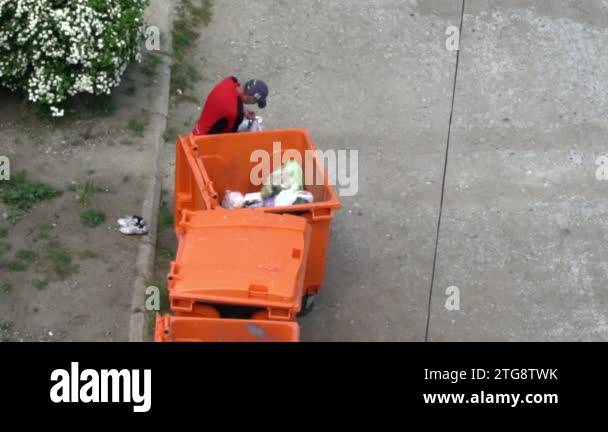 Homeless man rummages through the garbage can and looks for food and ...