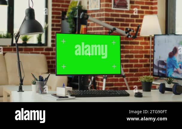 Greenscreen display on computer with empty desk in living room, workspace with chroma key blank ...