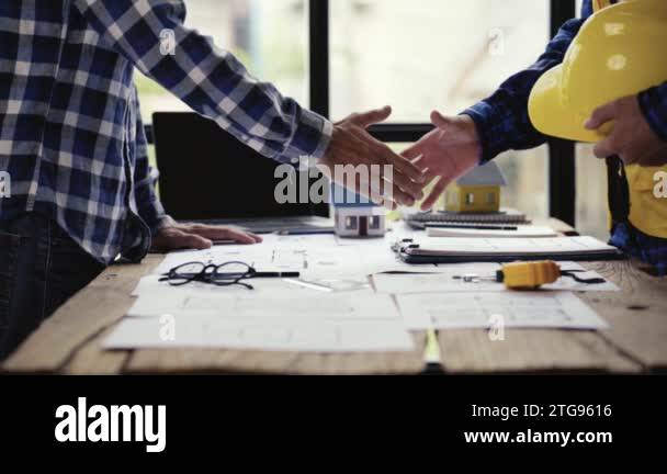 Two Civil Engineer or Architect holding helmet and handshaking after a ...