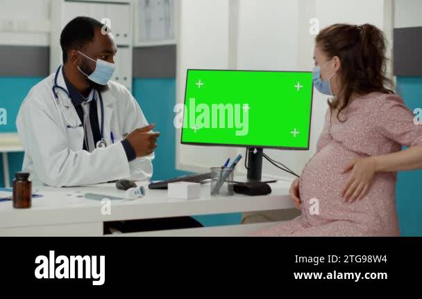 Doctor and patient with pregnancy belly looking at greenscreen on ...