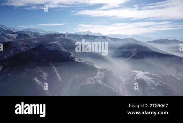 Fog rises on the slopes of the mountains. From above, white clouds ...