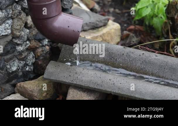 Rain water flows out of the gutter pipe. Roof gutter system on the ...