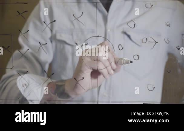Soccer coach drawing soccer tactics on glass with black marker ...