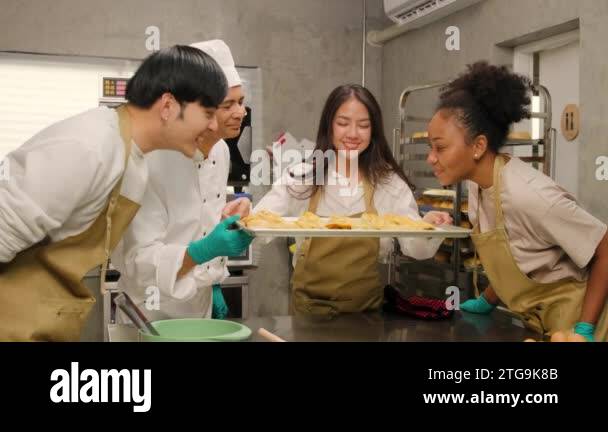 Young Asian female cooking class student shows tray of baked pies from ...