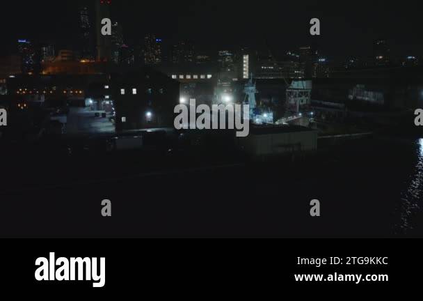 Forwards fly above docks at waterfront. Glowing lights shining on boats ...