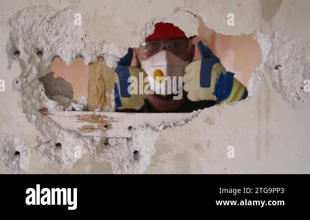 Contractor shows thumb up sign in a wall hole and has fun on apartment ...