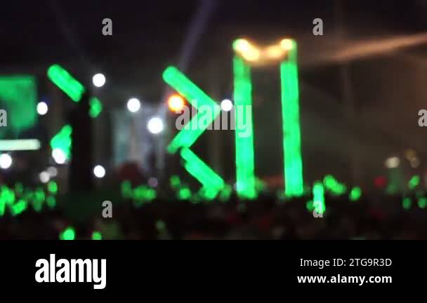 Crowd of people enjoying open air concert. Waving green light stick ...