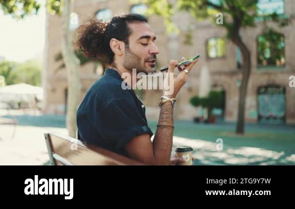 Attractive italian guy with ponytail and stubble is using mobile phone ...