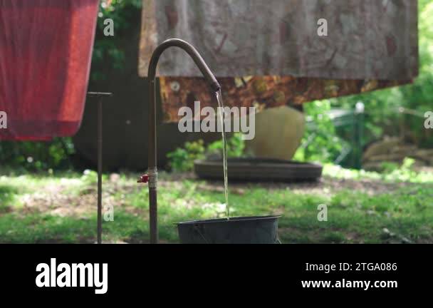 Running water flows into a bucket in the garden yard. Draw water from a ...