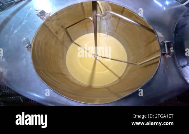 The process of stirring milk into a mixer at a factory. Stirring milk ...
