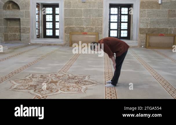 Muslim man praying in a mosque, bowing on his knees, performing ruku ...