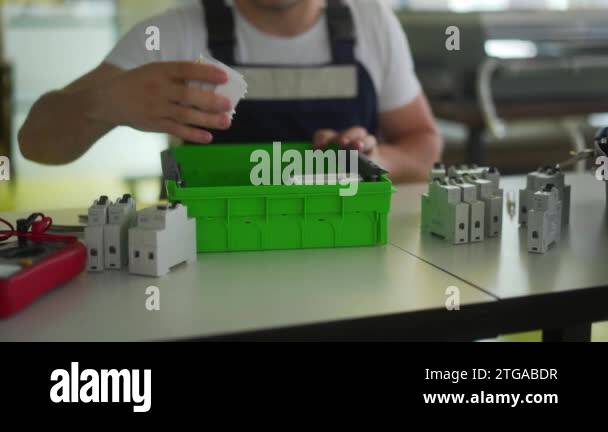 Electrician assembles electrical panel fuse box in workshop. Worker ...