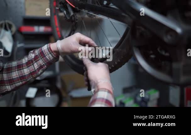Hands of a male bicycle mechanic in work clothes opens the lock of a ...
