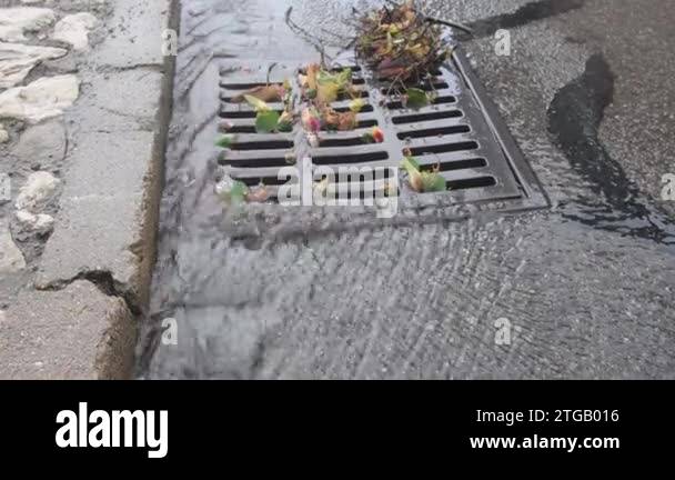 Water flows down through the manhole cover. Rain flows into a sewer ...