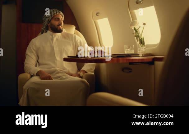 Muslim businessman enjoying airplane trip. Successful man checking hand ...