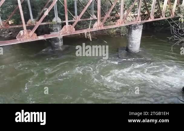 A An old rusty truss iron pole is standing overflowing river water in ...