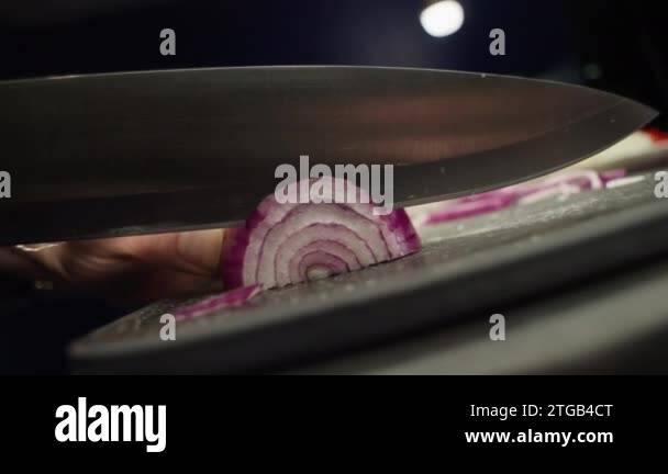 Slow-motion video close-up of slicing an onion with a knife on a ...