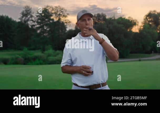 Rich golf player stand relaxed on course. Old man smoking cigar holding ...