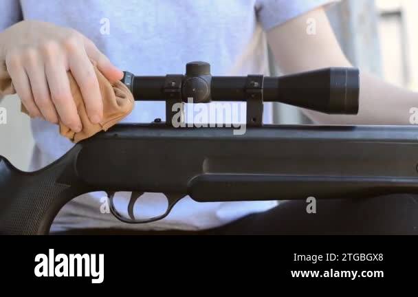 A female sniper cleans the optical sight of her rifle, close-up. Women ...