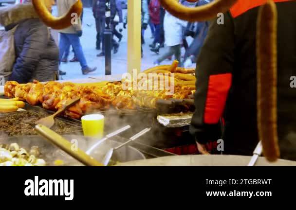 A chef prepares traditional meat dishes outdoors in a large frying pan ...