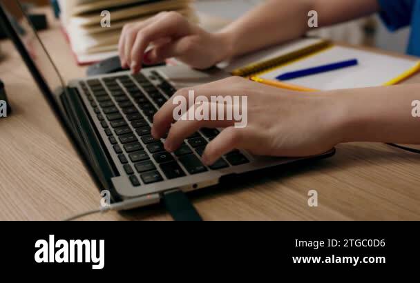 Close-up of a young boys hands tapping his fingers on a laptop keyboard ...