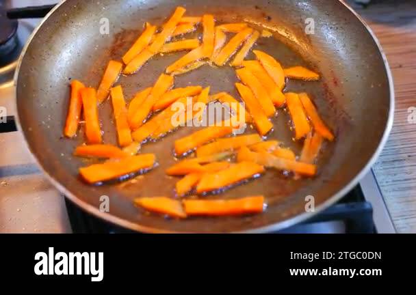 cutting carrots into slices. fried carrots in a pan. Sliced carrots and ...