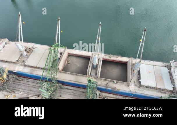 Loading dry cargo ship of sunflowers by cranes in port. Aerial view loading into holds of sea ...