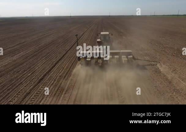Tractor on tillage in the field. Tractor sowing corn on ploughed land ...